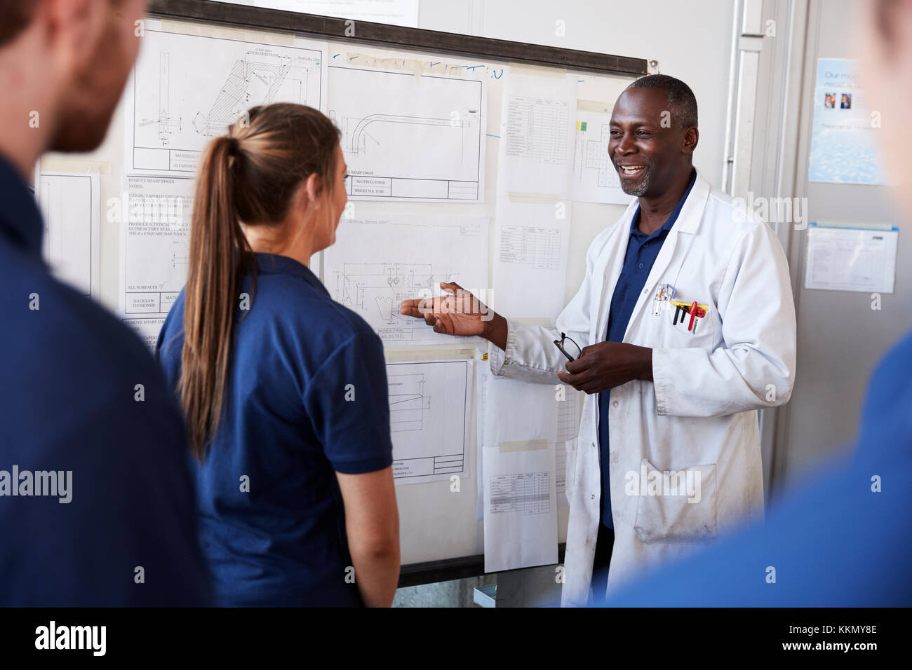 Engineer instructing apprentice at white board, close up Stock Photo ...