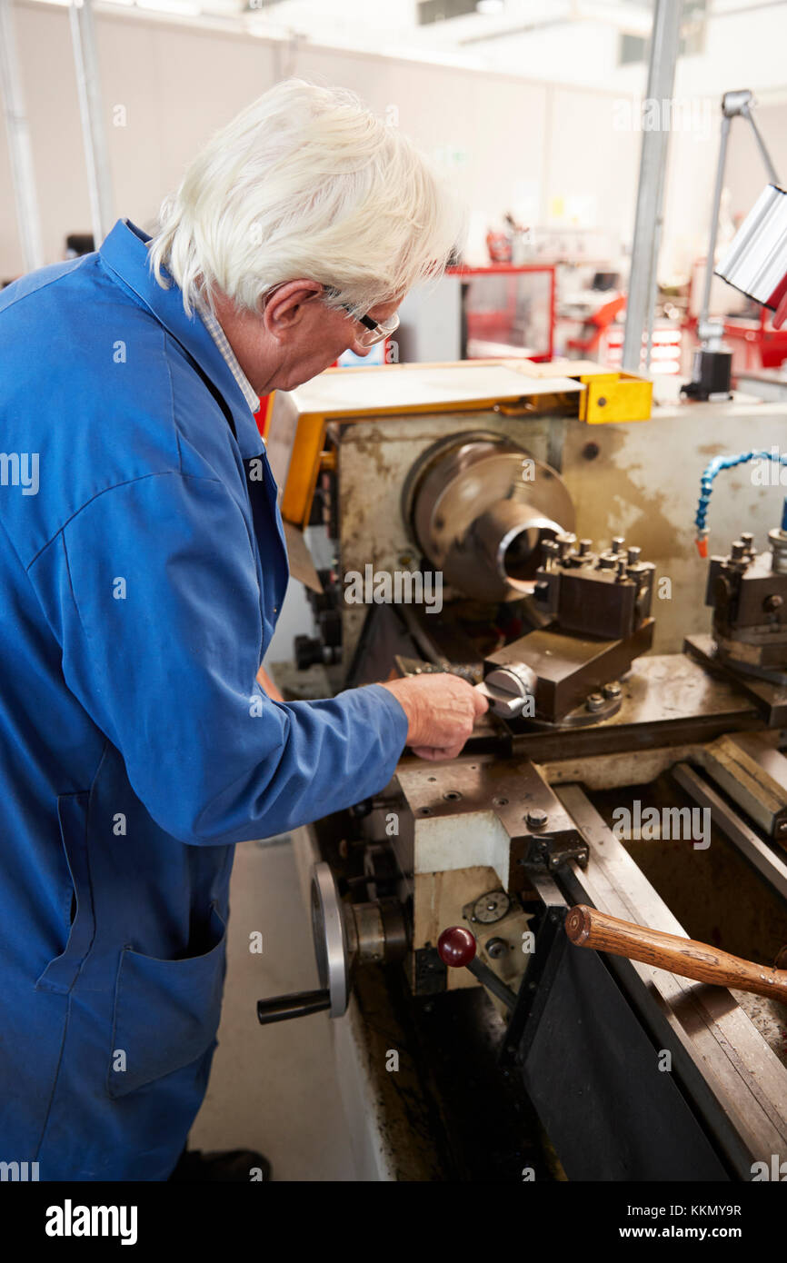 Senior engineer operating industrial machinery in a factory, vertical ...