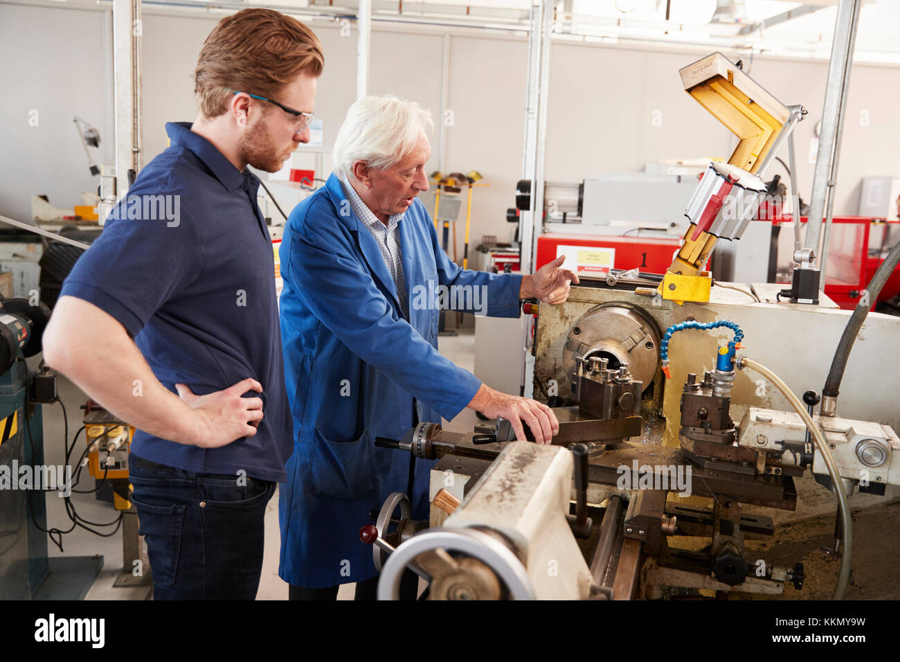 Senior engineer instructing apprentice at machine bench Stock Photo - Alamy