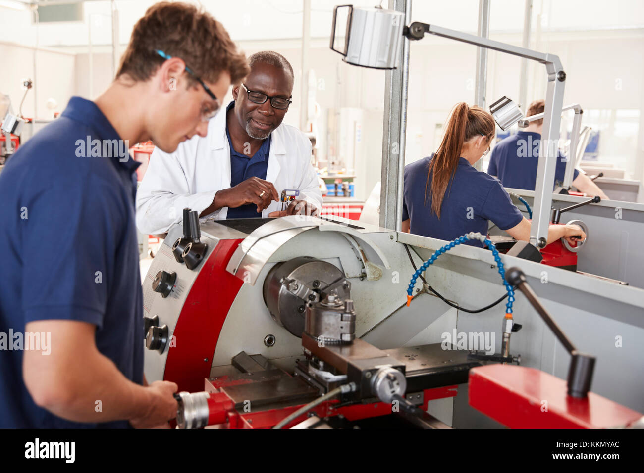 Engineer observing male apprentice work at his station Stock Photo - Alamy