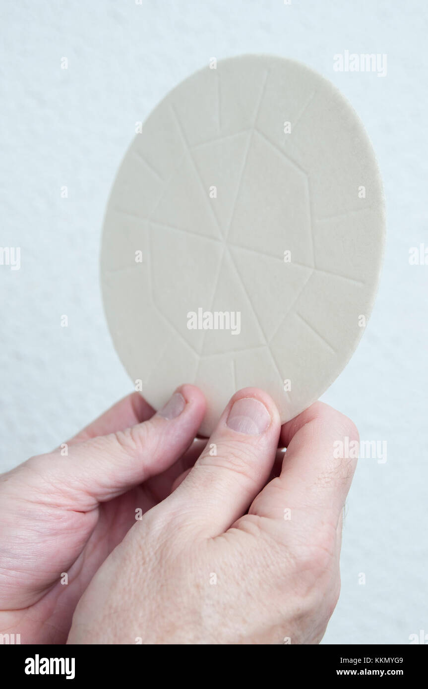A priests hands holds the host bread that is consecrated in the ...