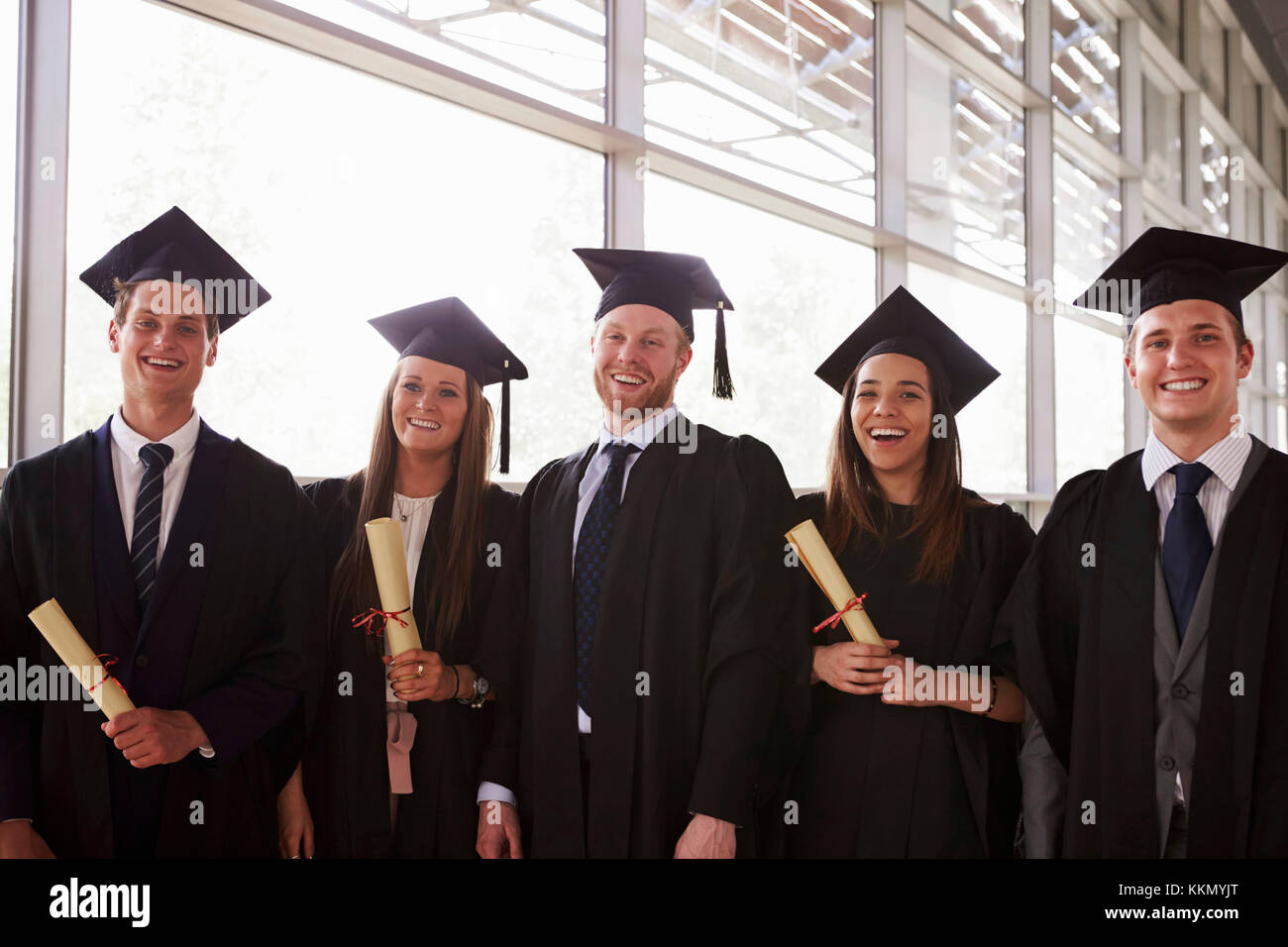 Five graduates in mortars and gowns holding certificates Stock Photo ...