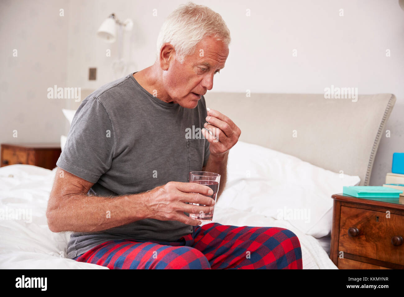 Senior Man Sitting On Bed At Home Taking Medication Stock Photo - Alamy