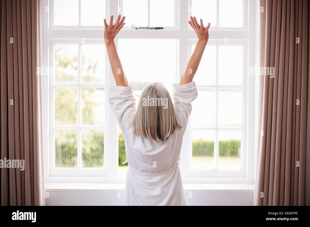 Rear View Of Senior Woman Stretching In Front Of Bedroom Window Stock ...