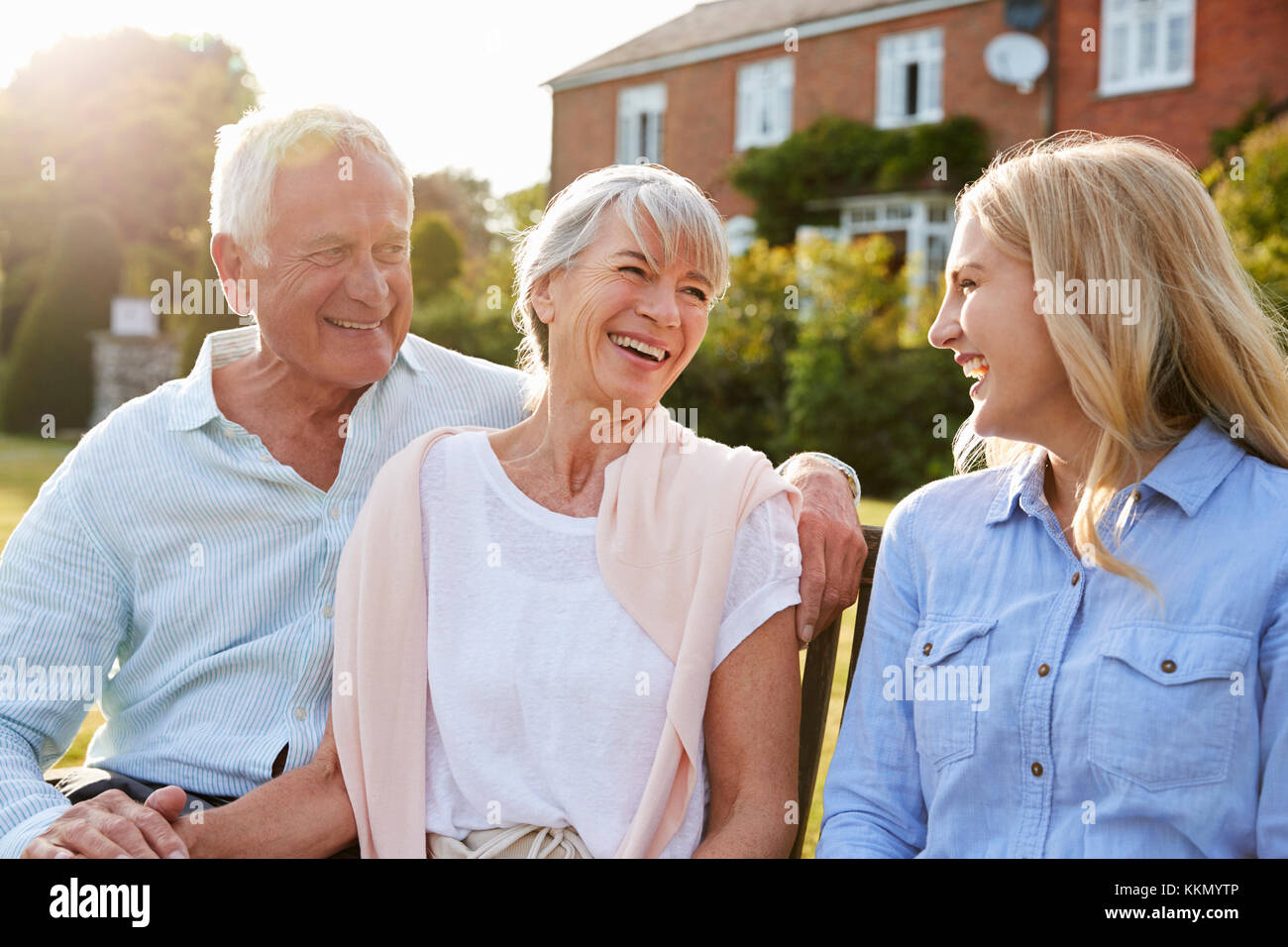 Senior Parents Sitting On Seat In Garden With Adult Daughter Stock ...