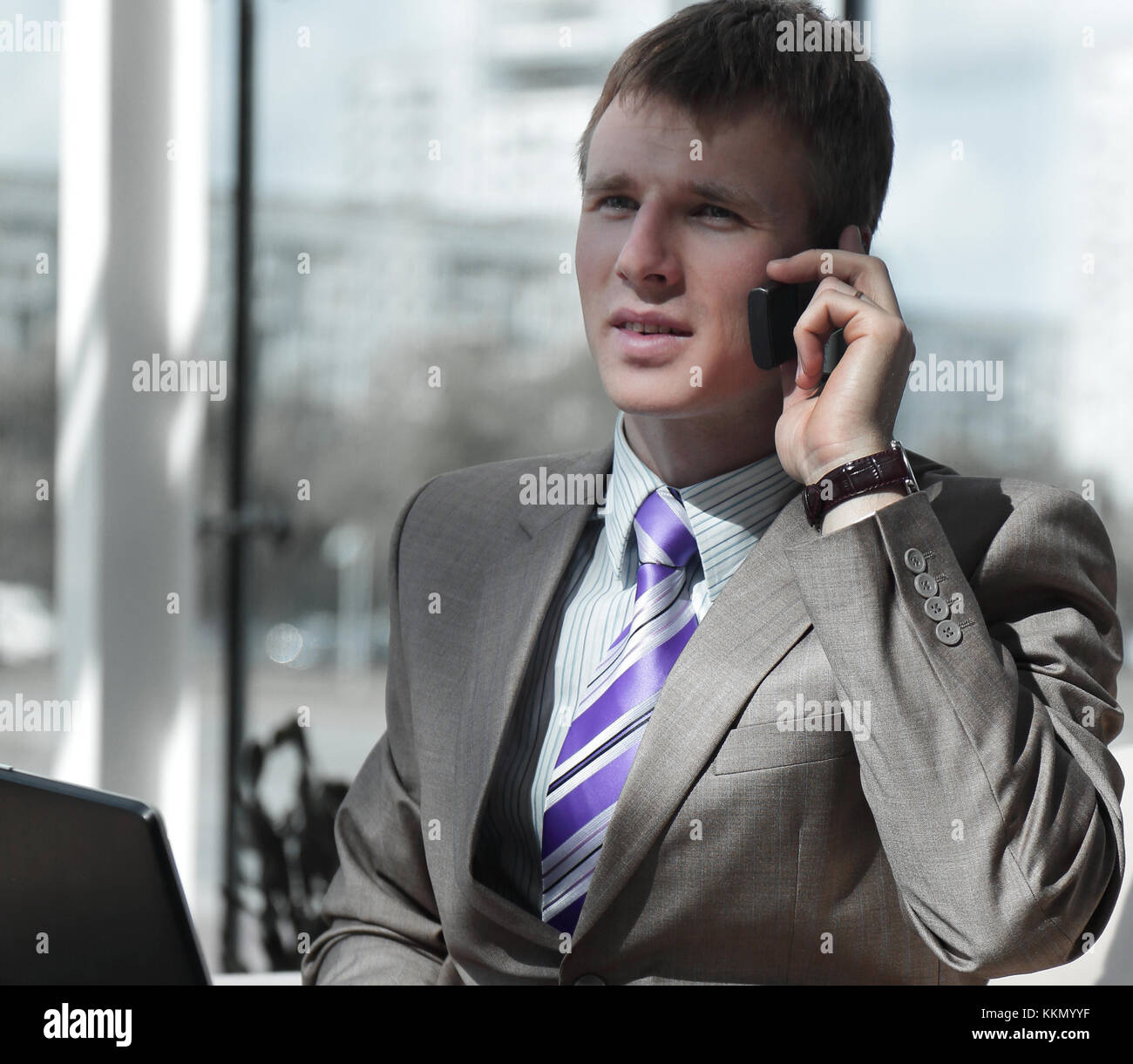 Attractive european guy talking on phone while using laptop Stock Photo ...