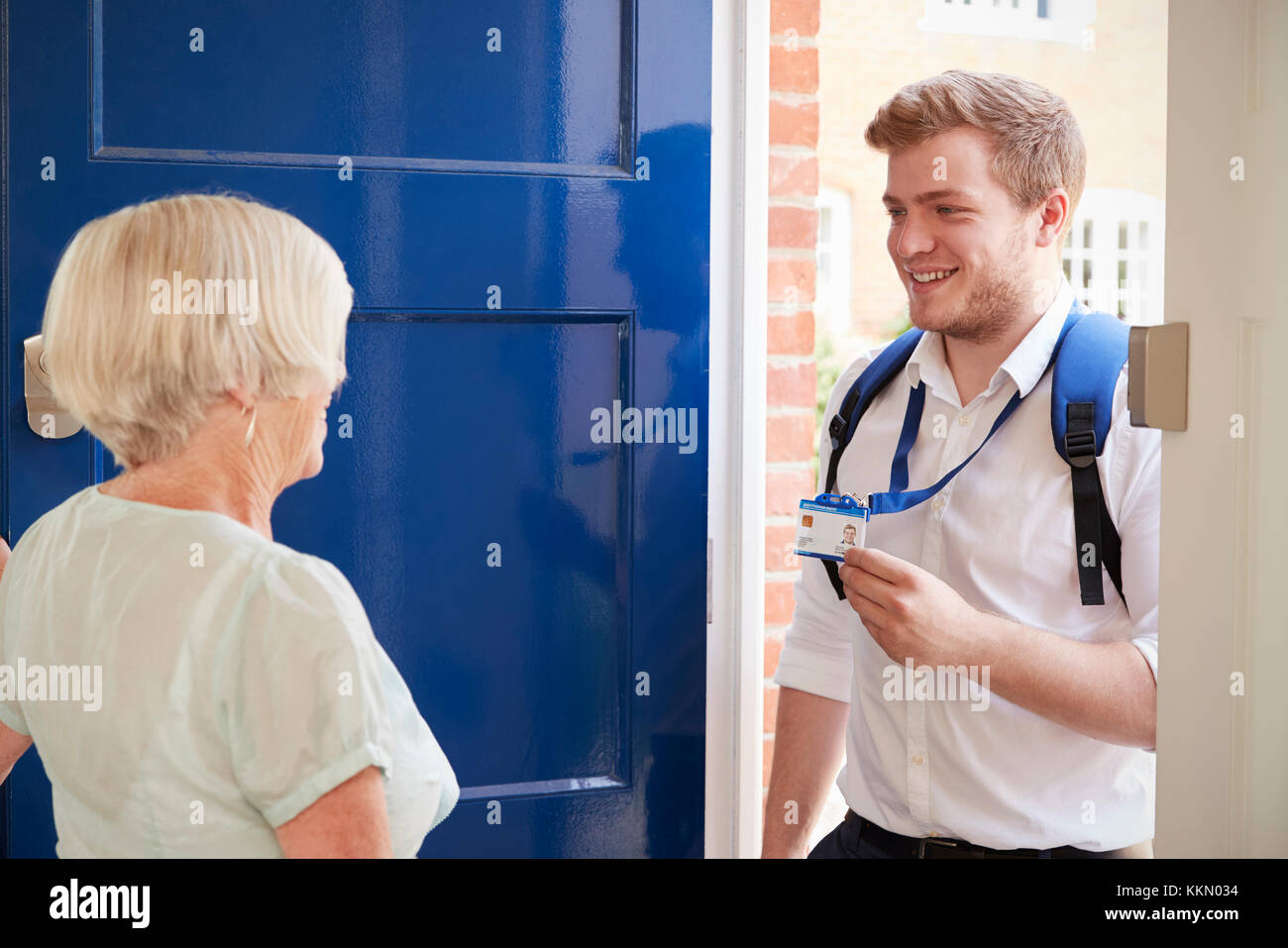Senior woman opens door to male care worker showing his ID Stock Photo ...