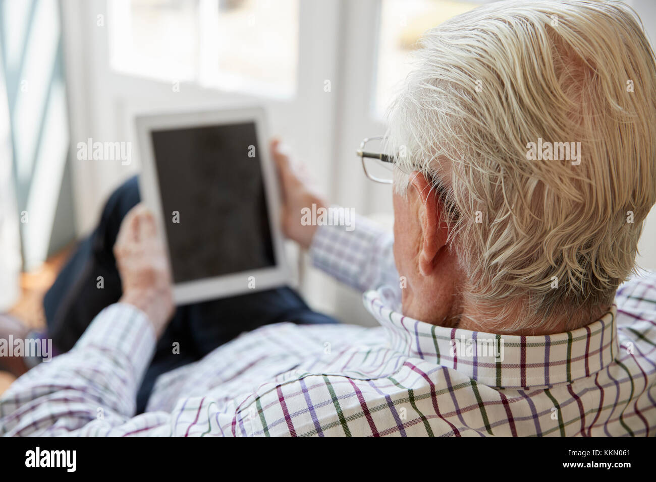 Senior man using tablet computer at home, over shoulder view Stock ...
