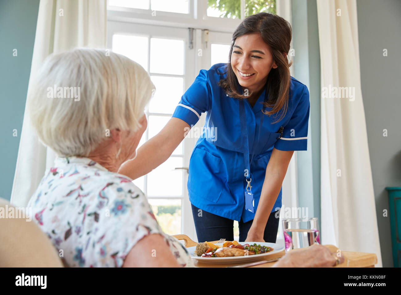 Care nurse serving dinner to a senior woman at home Stock Photo - Alamy