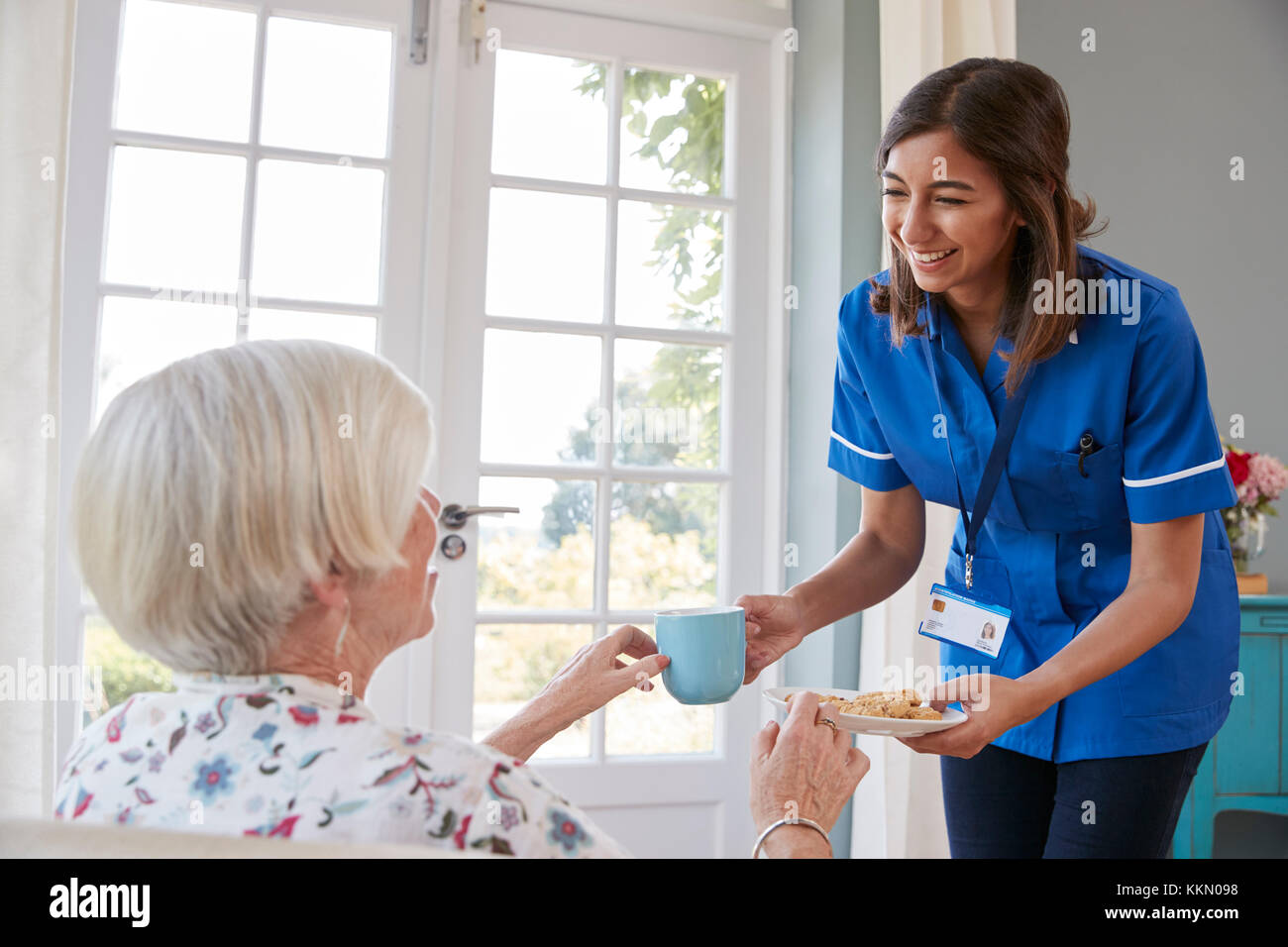Nurse serving tea to senior woman at home, close up Stock Photo - Alamy