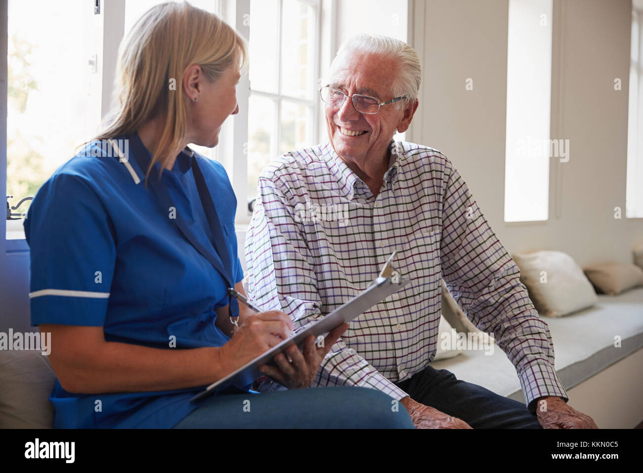 Senior man sits with nurse making notes at retirement home Stock Photo ...