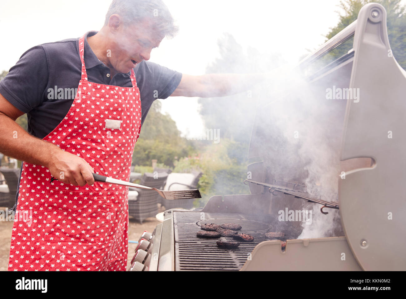 Middle aged man burning food on a barbecue Stock Photo - Alamy