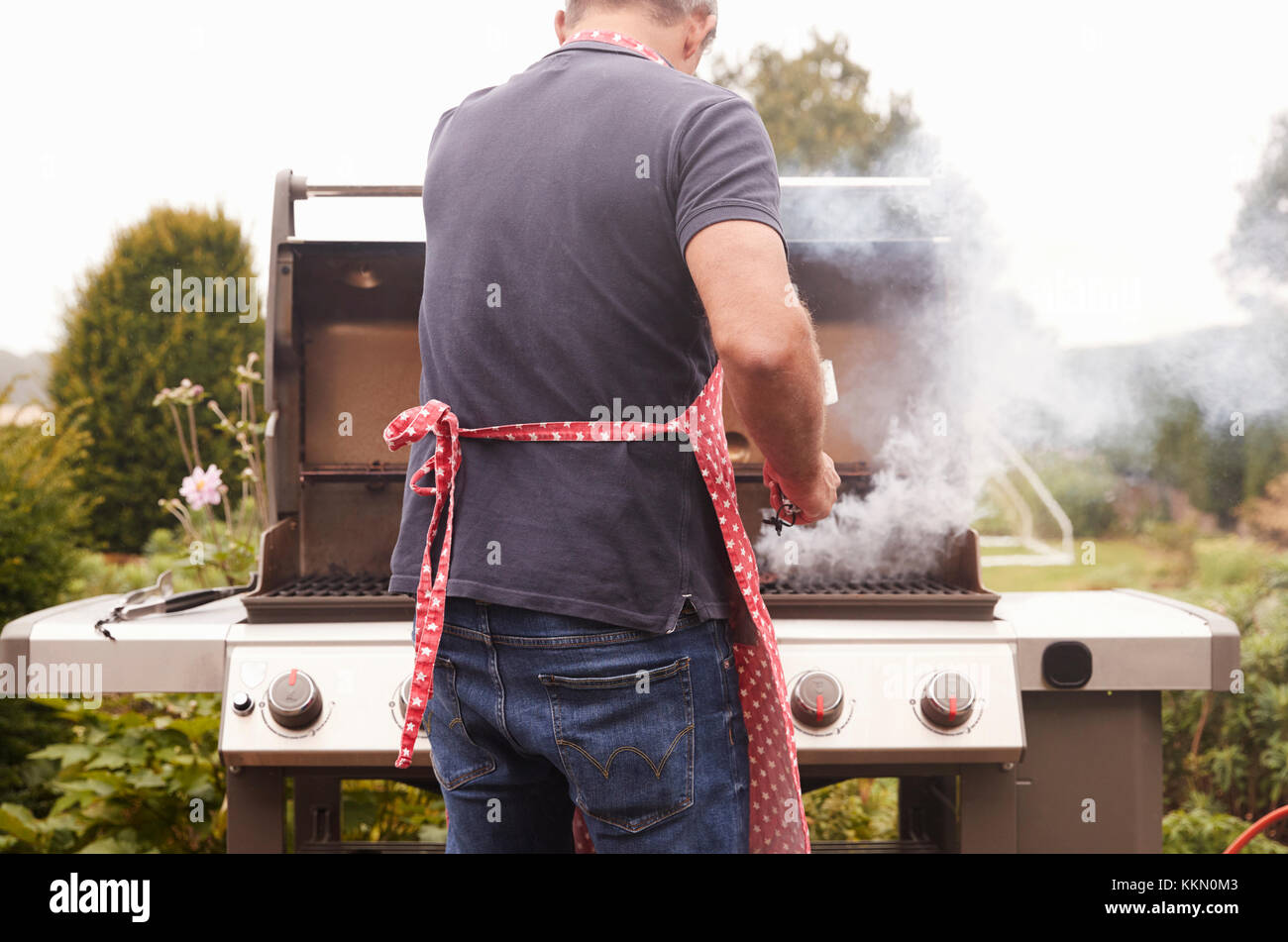 Middle aged man burning food on a barbecue, back view Stock Photo - Alamy