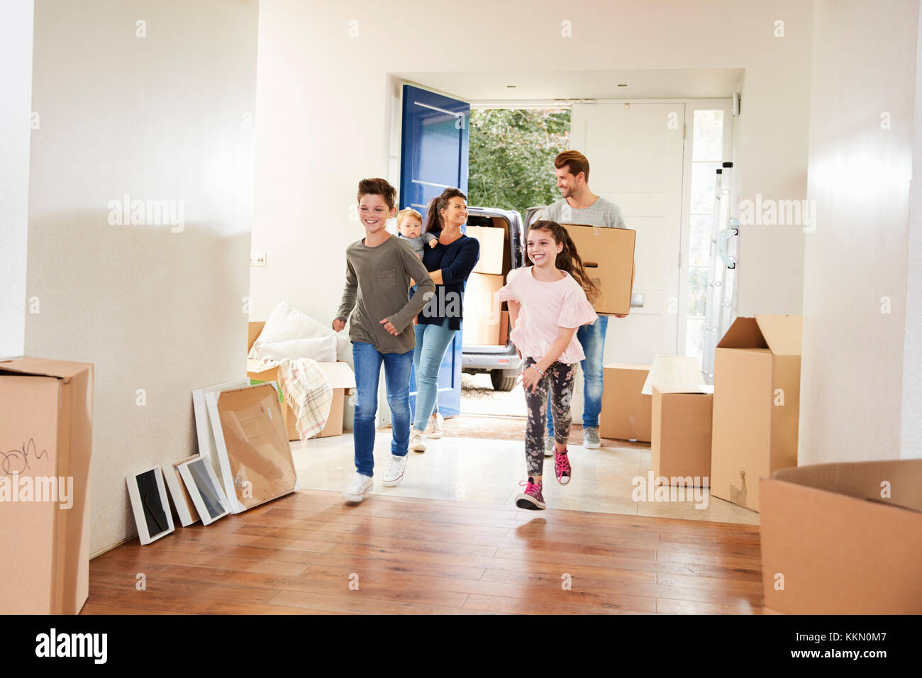 Family Carrying Boxes Into New Home On Moving Day Stock Photo - Alamy