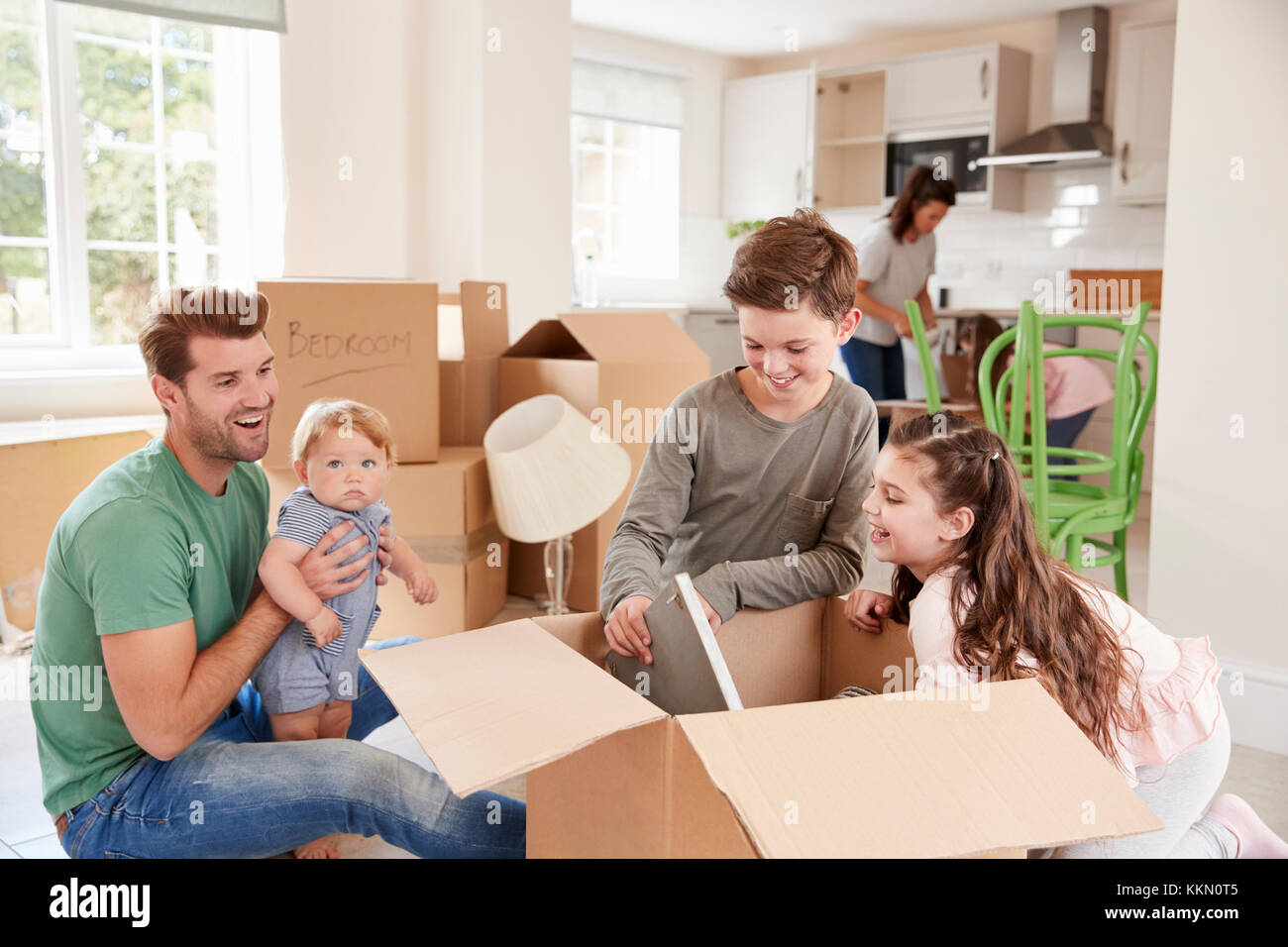 Children Helping Parents To Unpack On Moving In Day Stock Photo - Alamy