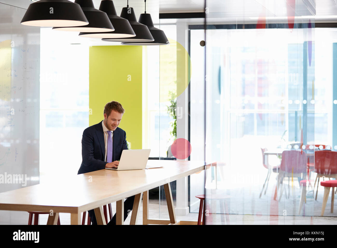 Young white man working alone in an office meeting area Stock Photo - Alamy