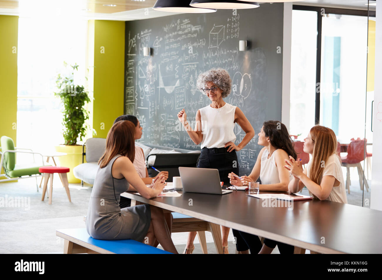 Female boss standing at an informal team meeting Stock Photo - Alamy