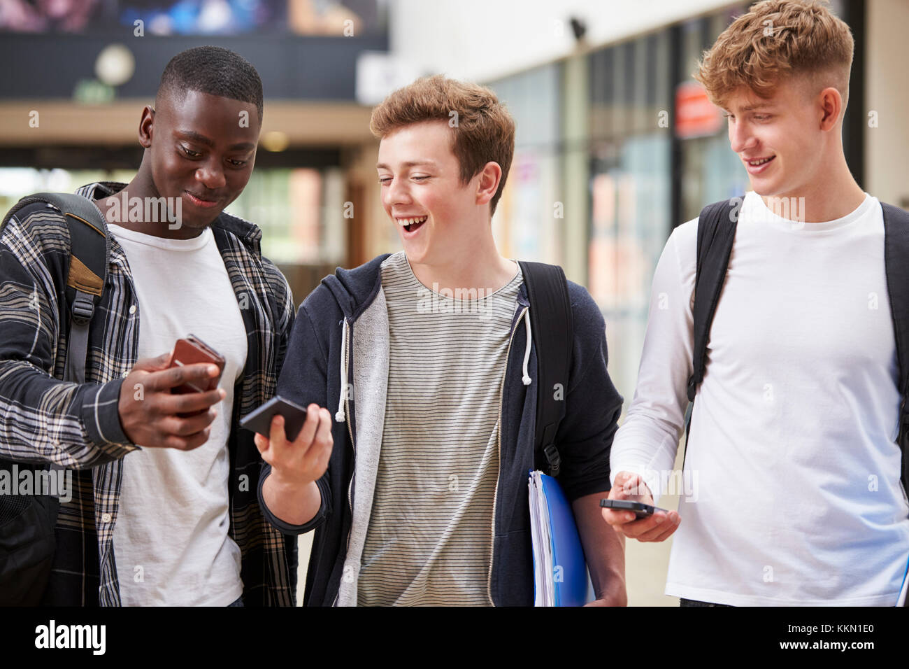 Three Male College Students Reading Text Message On Mobile Phone Stock ...