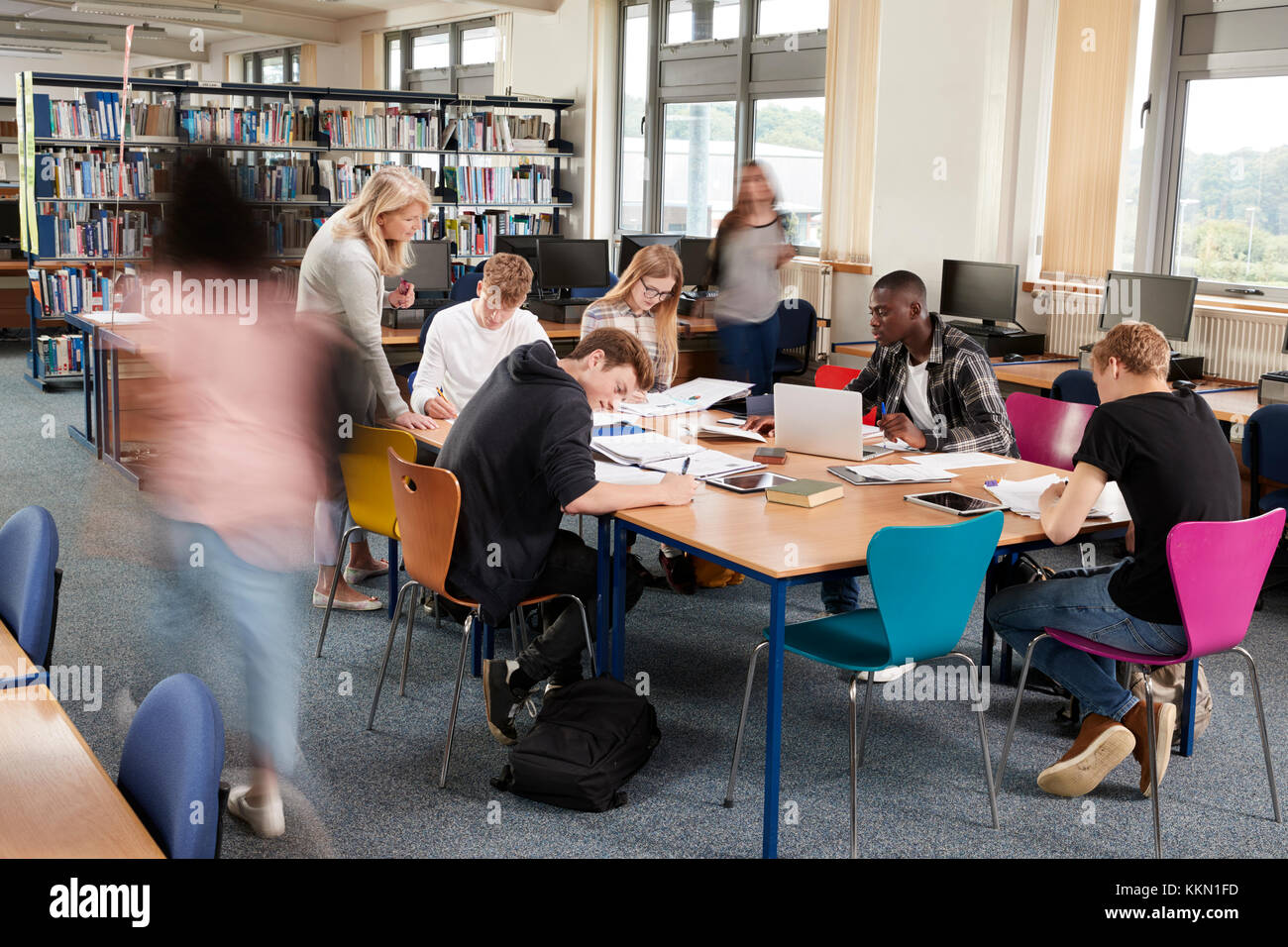 Busy College Library With Teacher Helping Students At Table Stock Photo ...