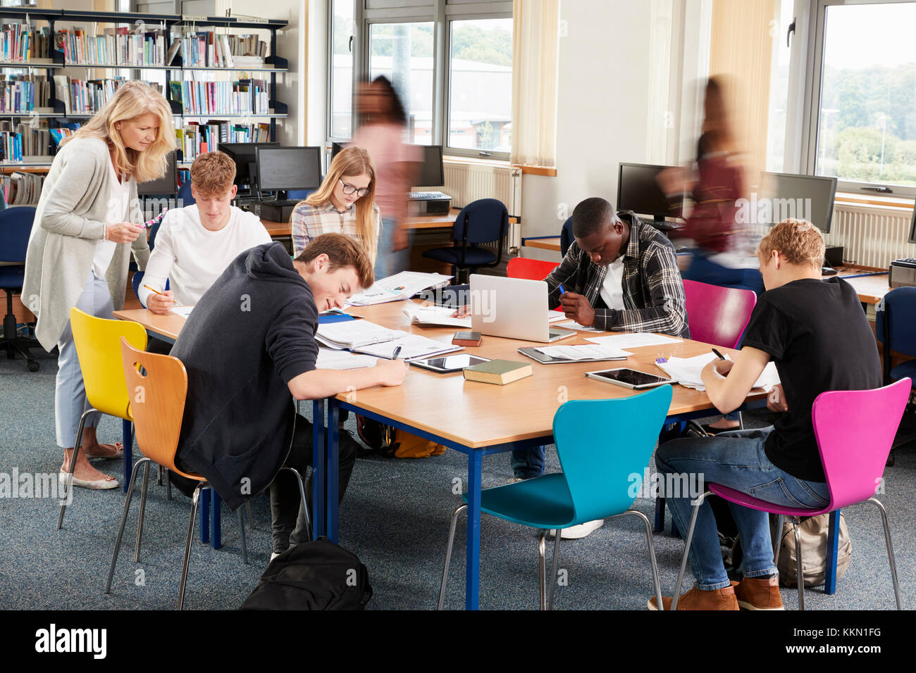 Busy College Library With Teacher Helping Students At Table Stock Photo ...