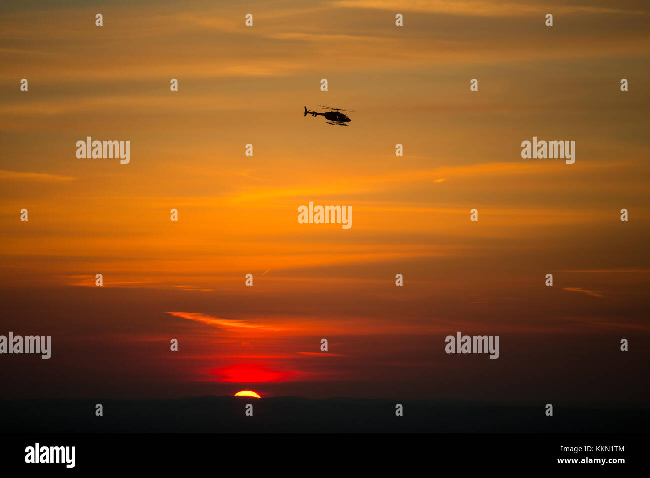Silhouette of a helicopter against sun at dusk Stock Photo - Alamy