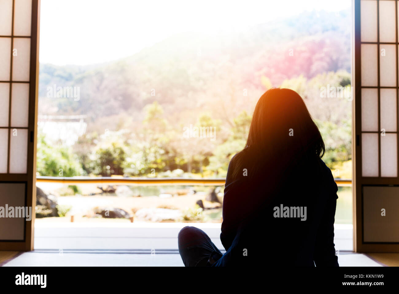 Young lady seated inside a room of a temple looking outside at the ...