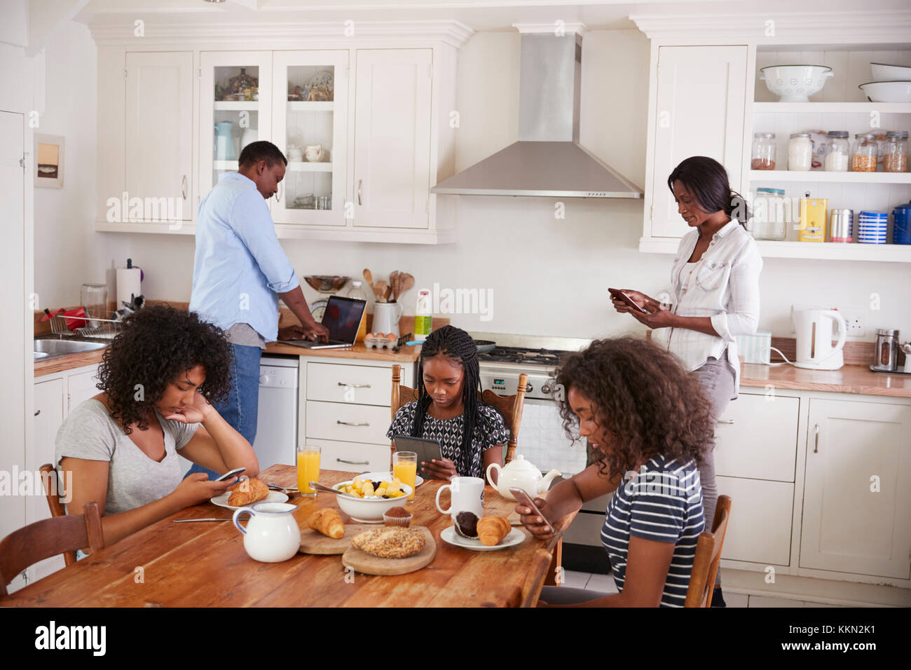 Family Sitting Around Breakfast Table Using Digital Devices Stock Photo ...