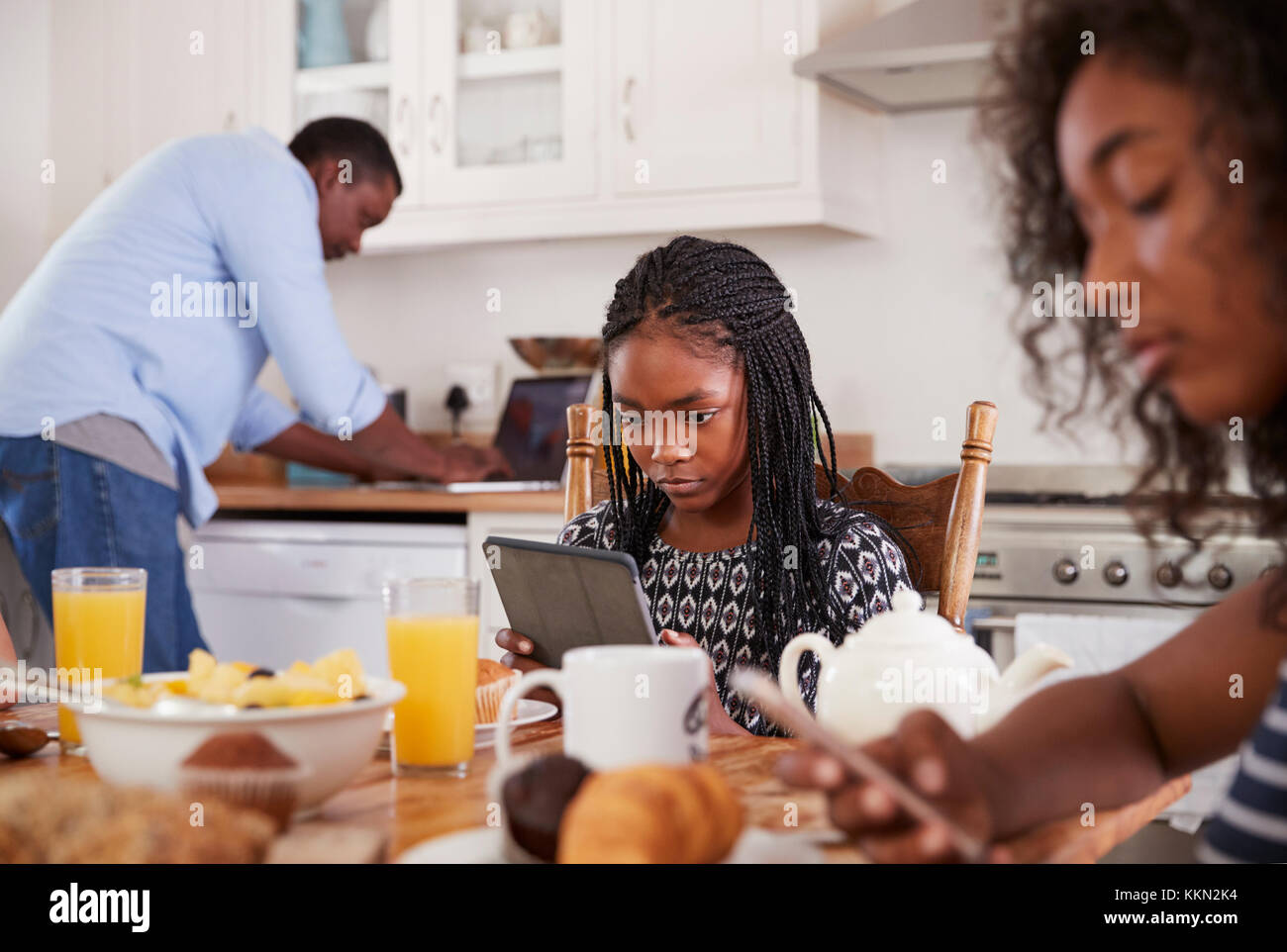 Family Sitting Around Breakfast Table Using Digital Devices Stock Photo ...