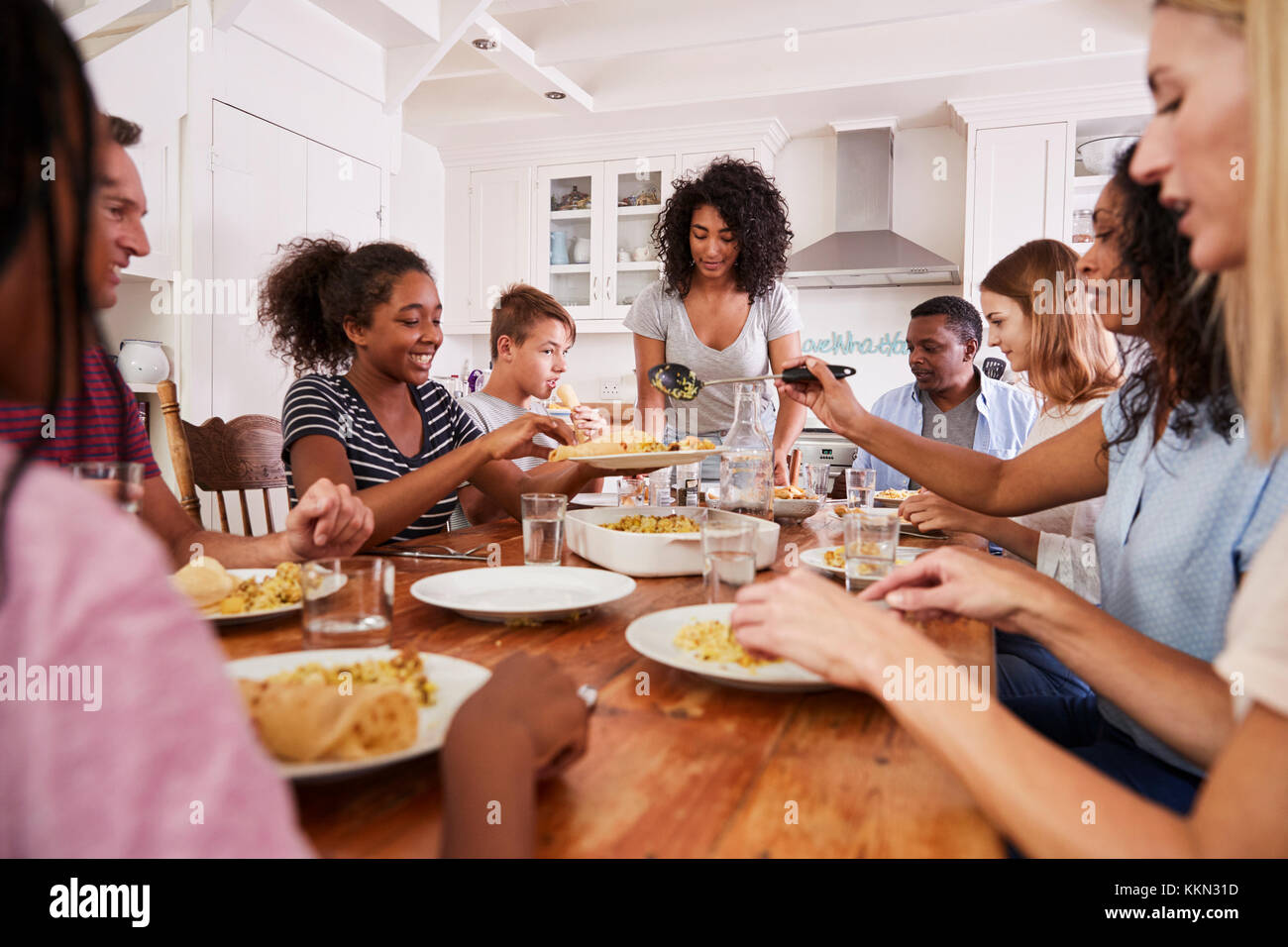 Two Families Enjoying Eating Meal At Home Together Stock Photo - Alamy