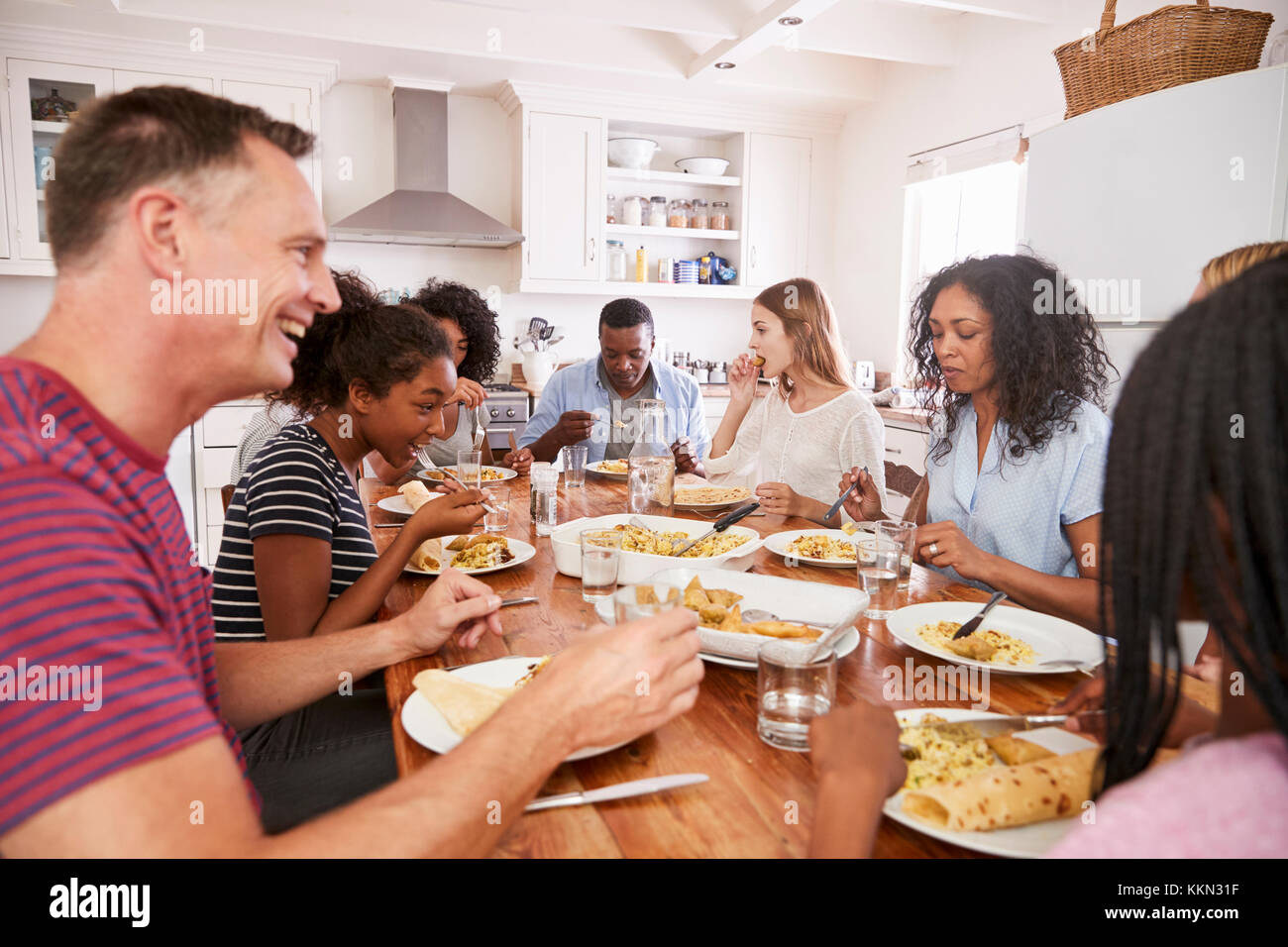 Two Families Enjoying Eating Meal At Home Together Stock Photo - Alamy