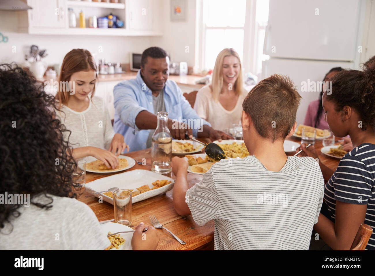 Two Families Enjoying Eating Meal At Home Together Stock Photo - Alamy