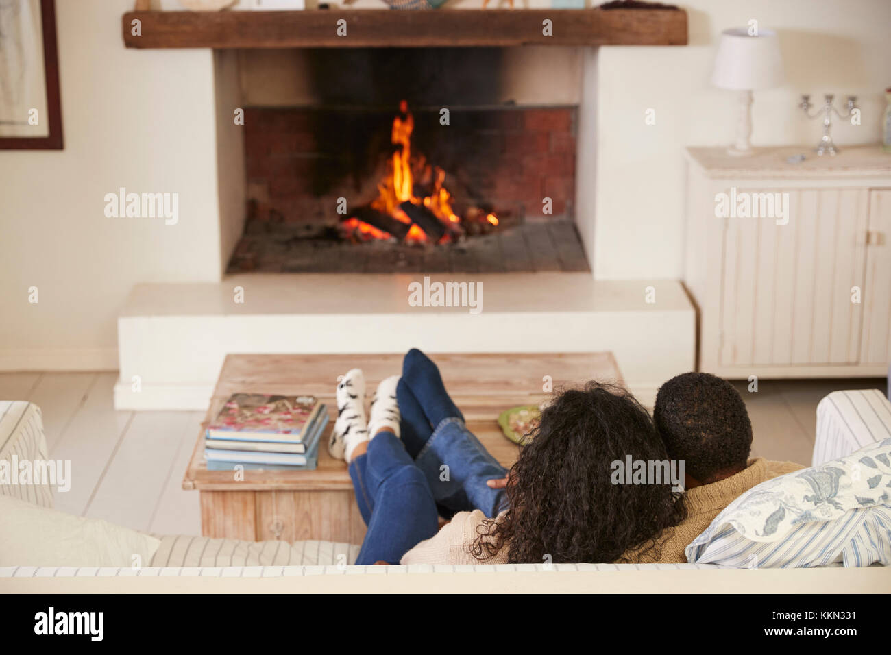 Romantic Couple Relaxing In Lounge Next To Open Fire Stock Photo - Alamy