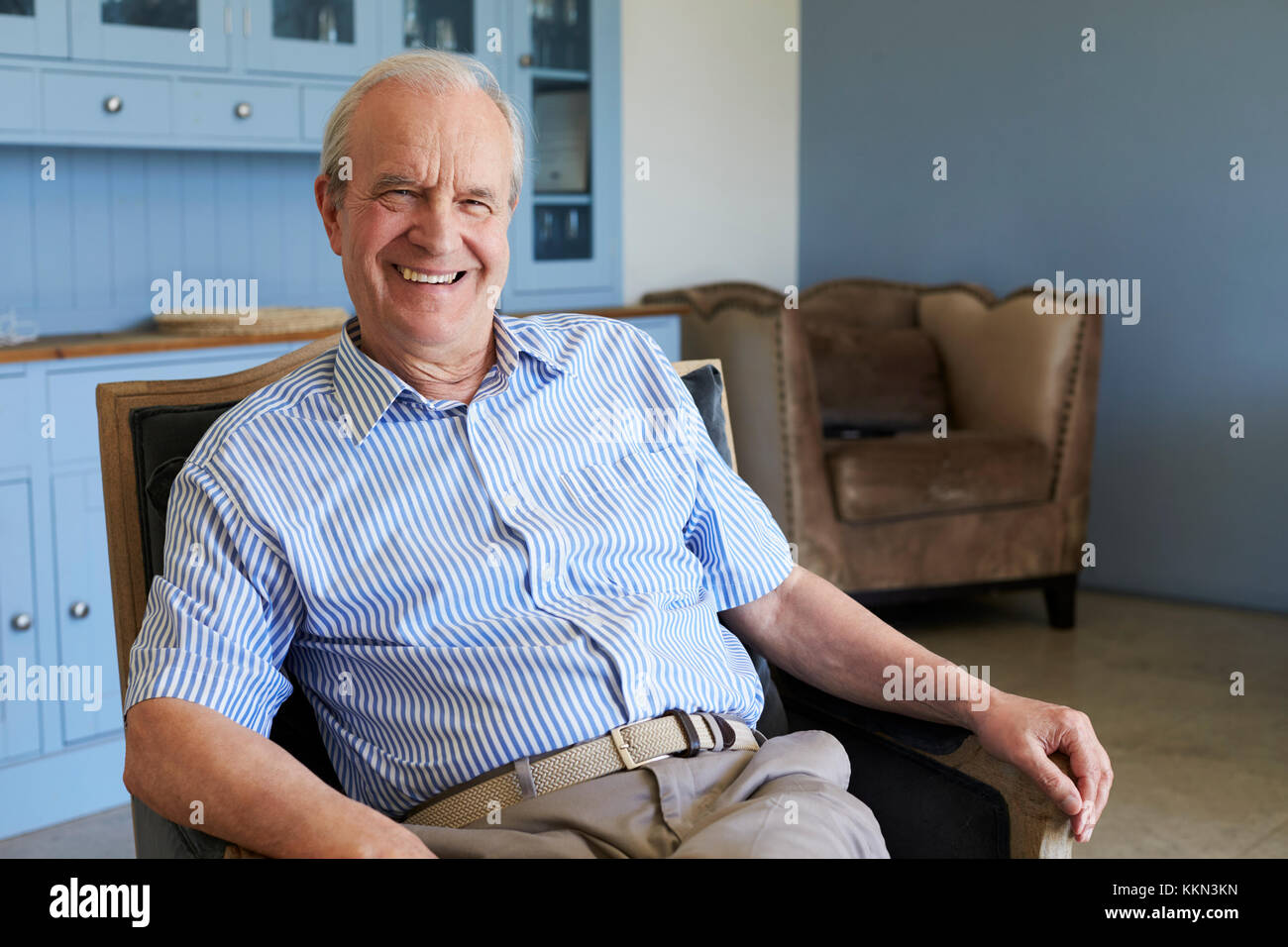 Portrait Of Smiling Senior Man Sitting In Chair At Home Stock Photo - Alamy