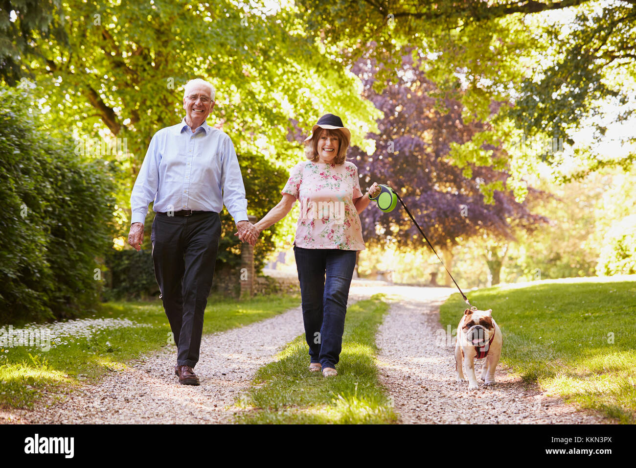 Portrait Of Senior Couple Walking Pet Bulldog In Countryside Stock ...