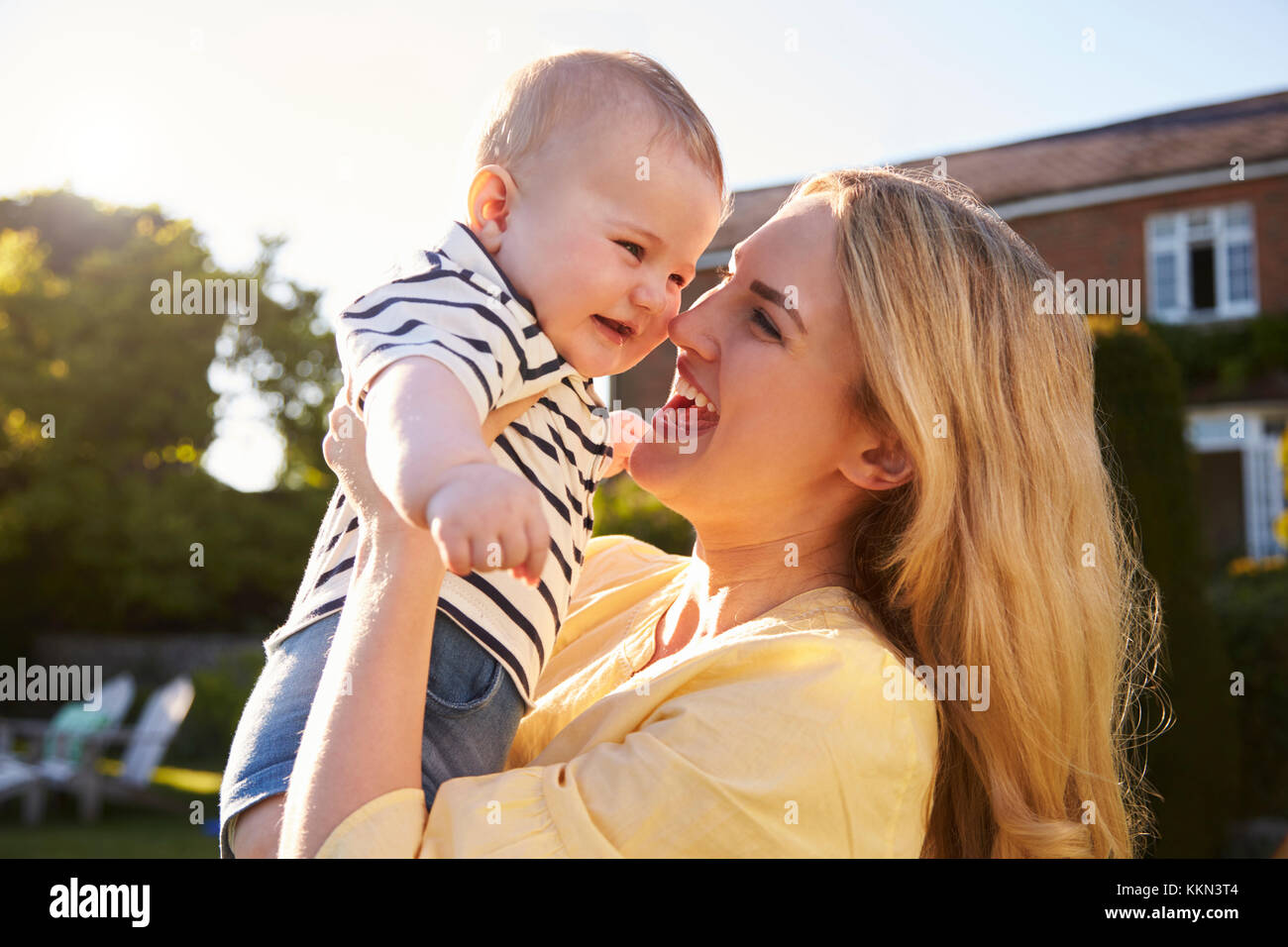 Young Mother Carrying Baby Son Outdoors In Summer Garden Stock Photo ...