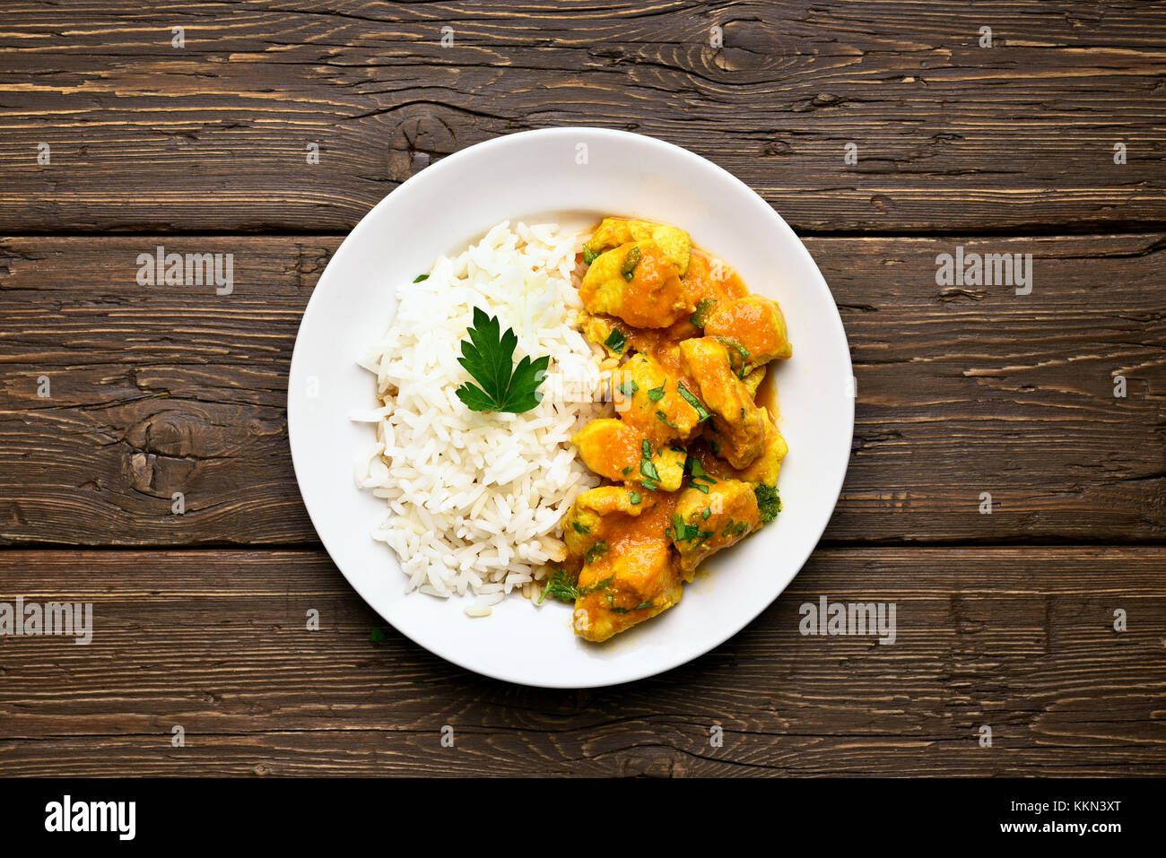Curry chicken with rice on plate over wooden background. Top view, flat ...