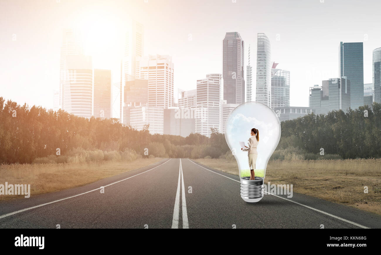 Young businesswoman trapped inside of light bulb on asphalt road Stock ...