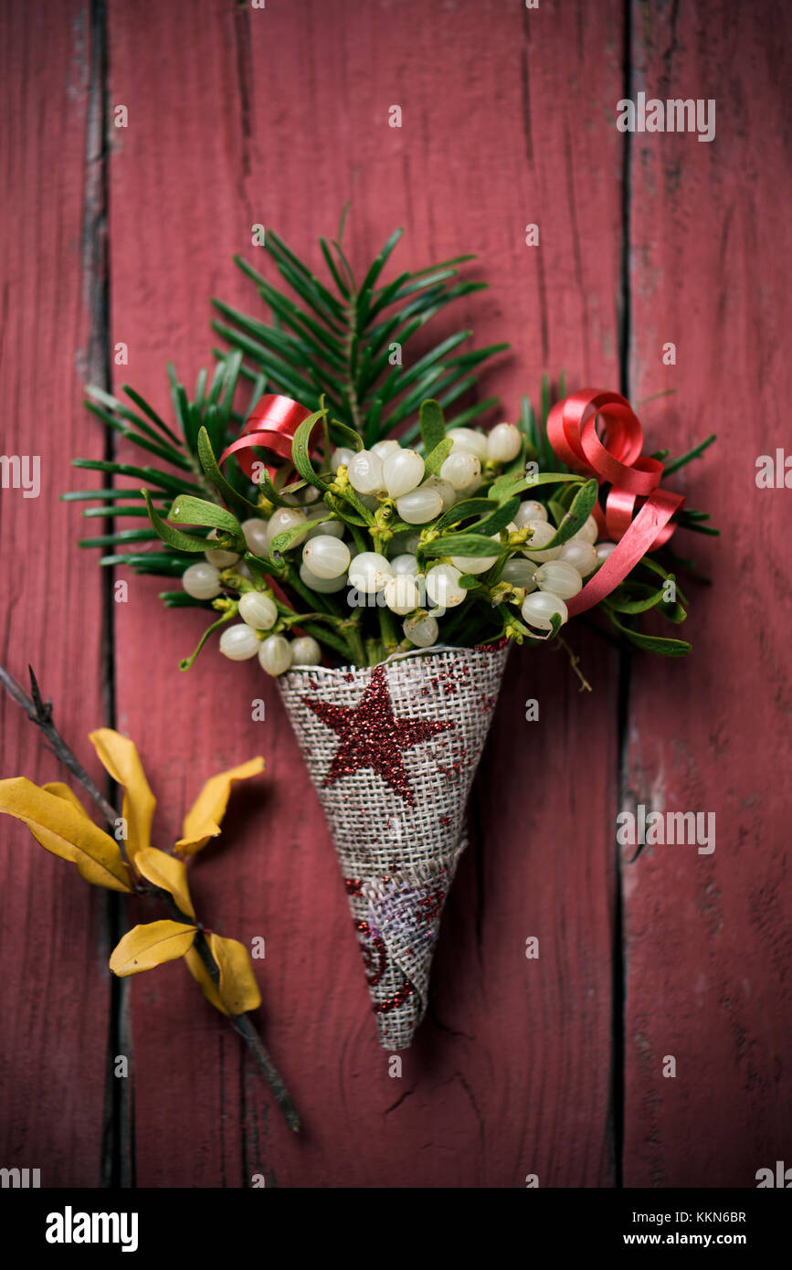 closeup of a bunch of mistletoe wrapped in a festive fabric, on a red ...