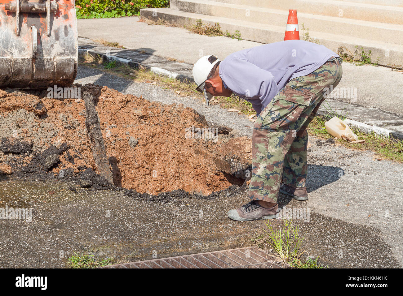Plumbing Repair Man and excavator scoop digging, Worker using a small ...
