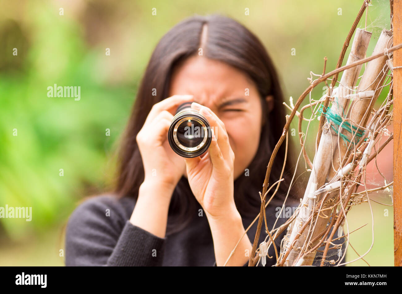 Young woman looking through black monocular in the forest in a blurred ...