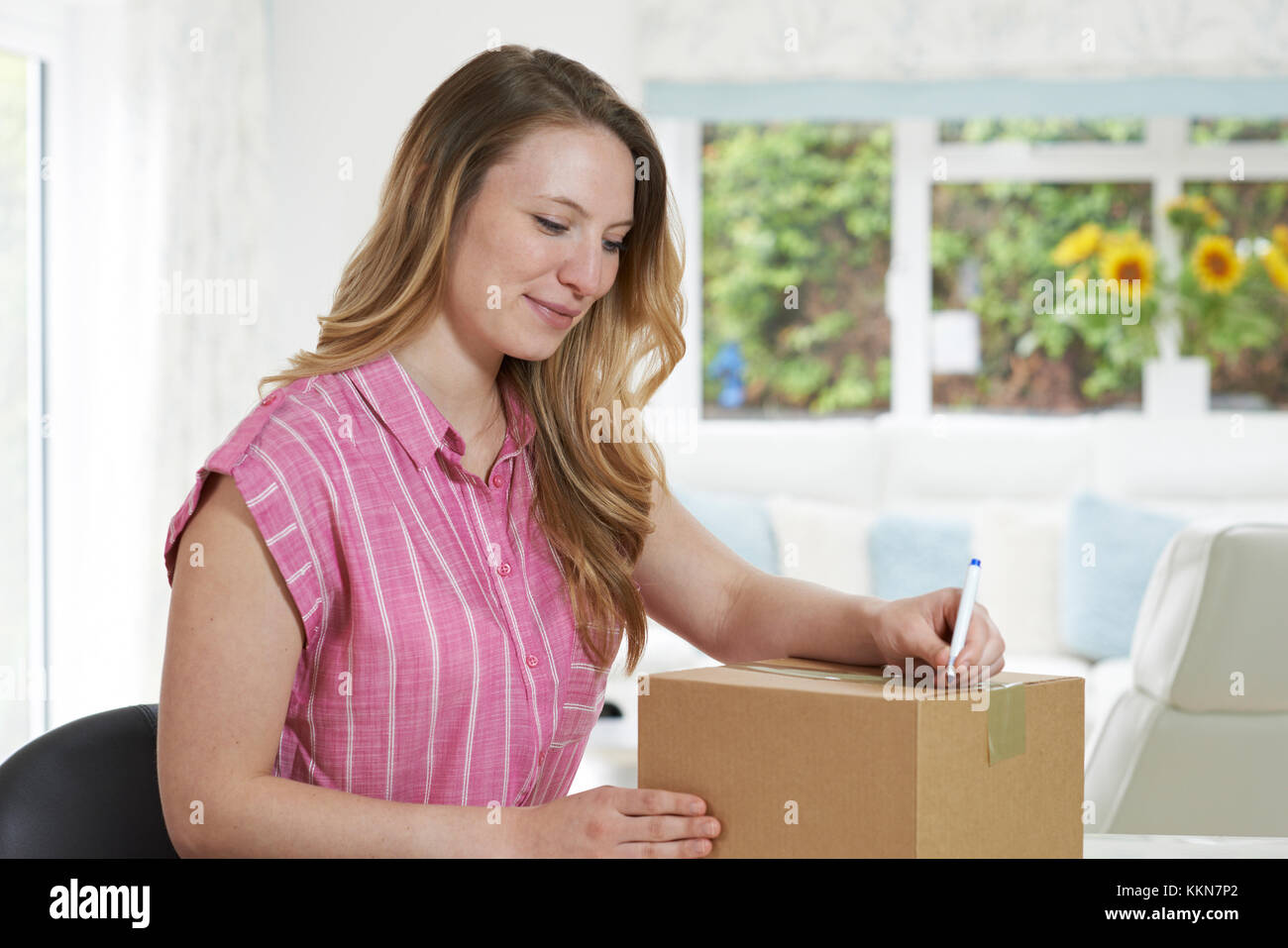 Woman At Home Writing Address On Package Stock Photo - Alamy