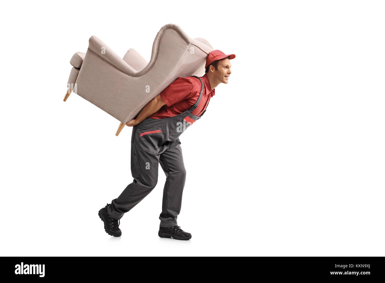 Full length profile shot of a mover walking and carrying an armchair on ...