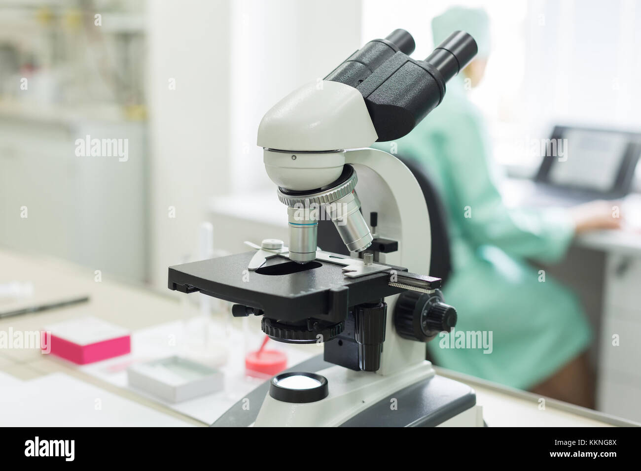 Microscope in the laboratory. Employee sitting at the table and working ...
