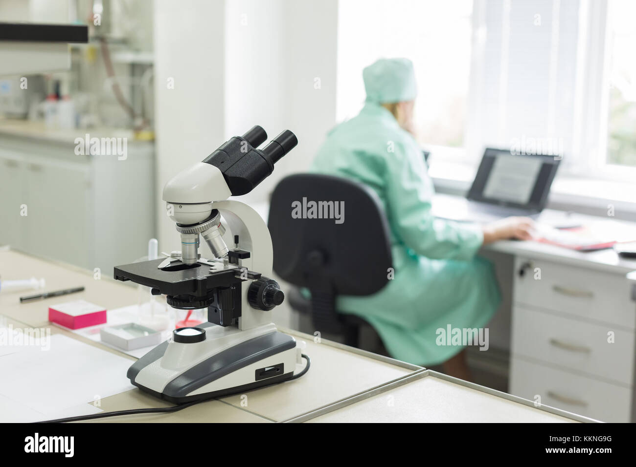 Microscope in the laboratory. Employee sitting at the table and working ...