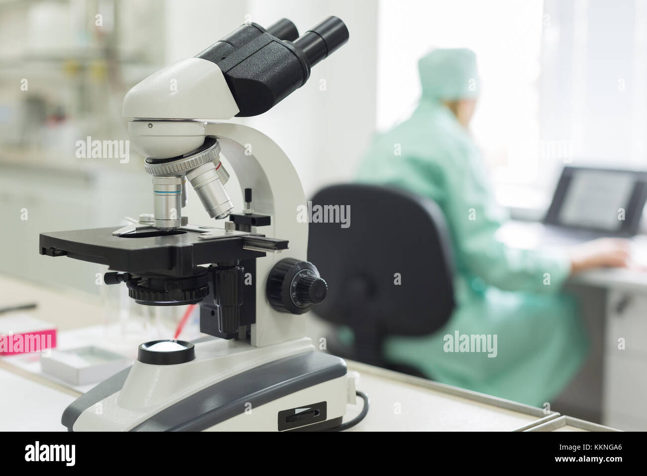 Microscope in the laboratory. Employee sitting at the table and working ...