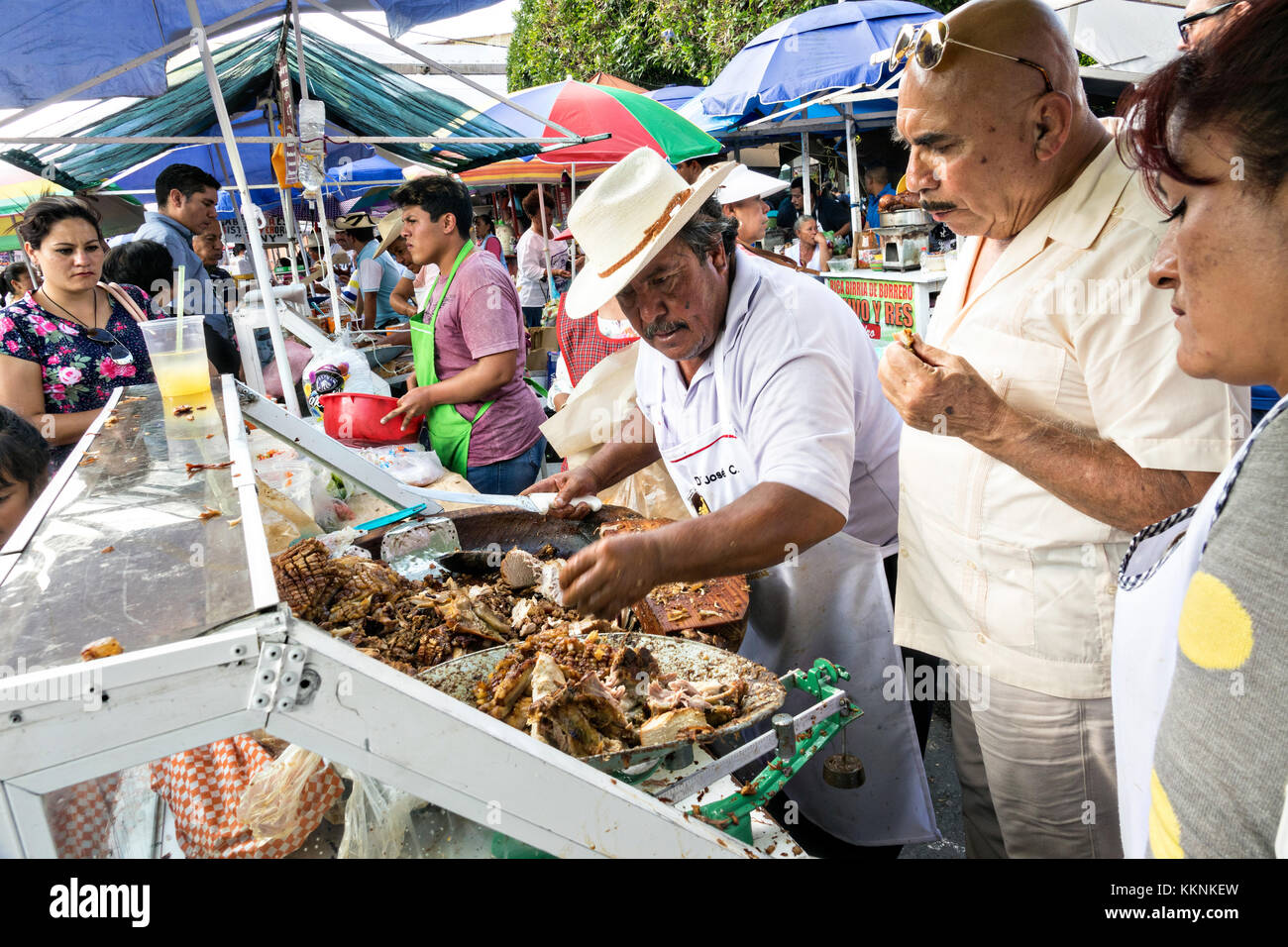 A Mexican butcher chops up freshly barbecued pork carnitas in the town ...