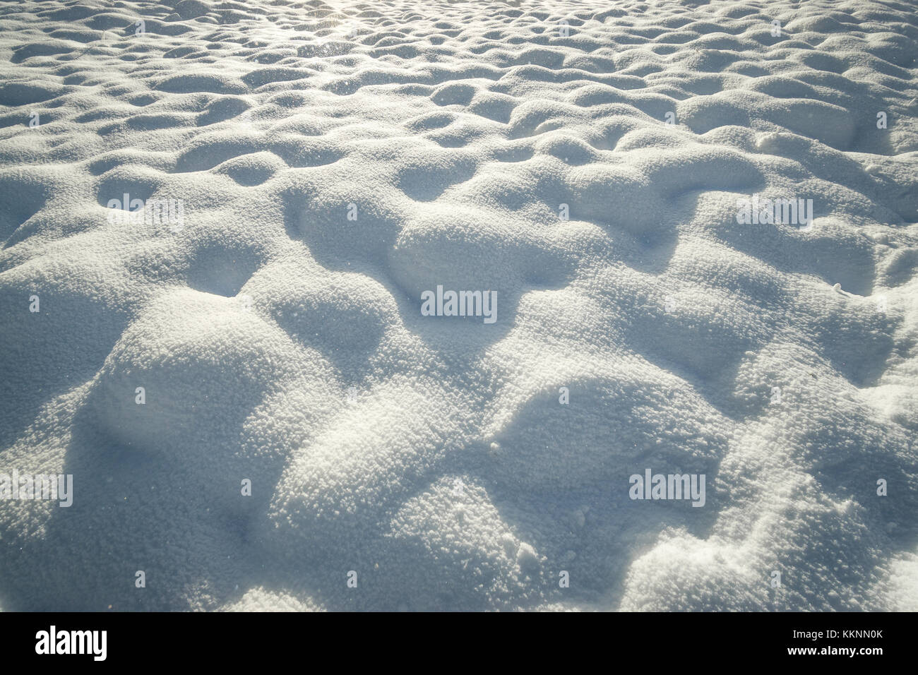 Fresh hilly snow surface background and drifting snowflakes. Bumpy snow ...