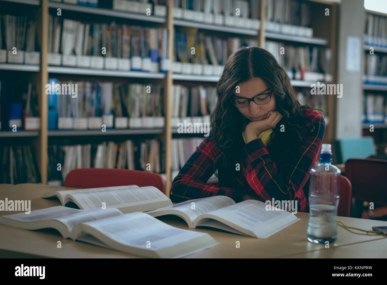 Girl reading book in library Stock Photo - Alamy