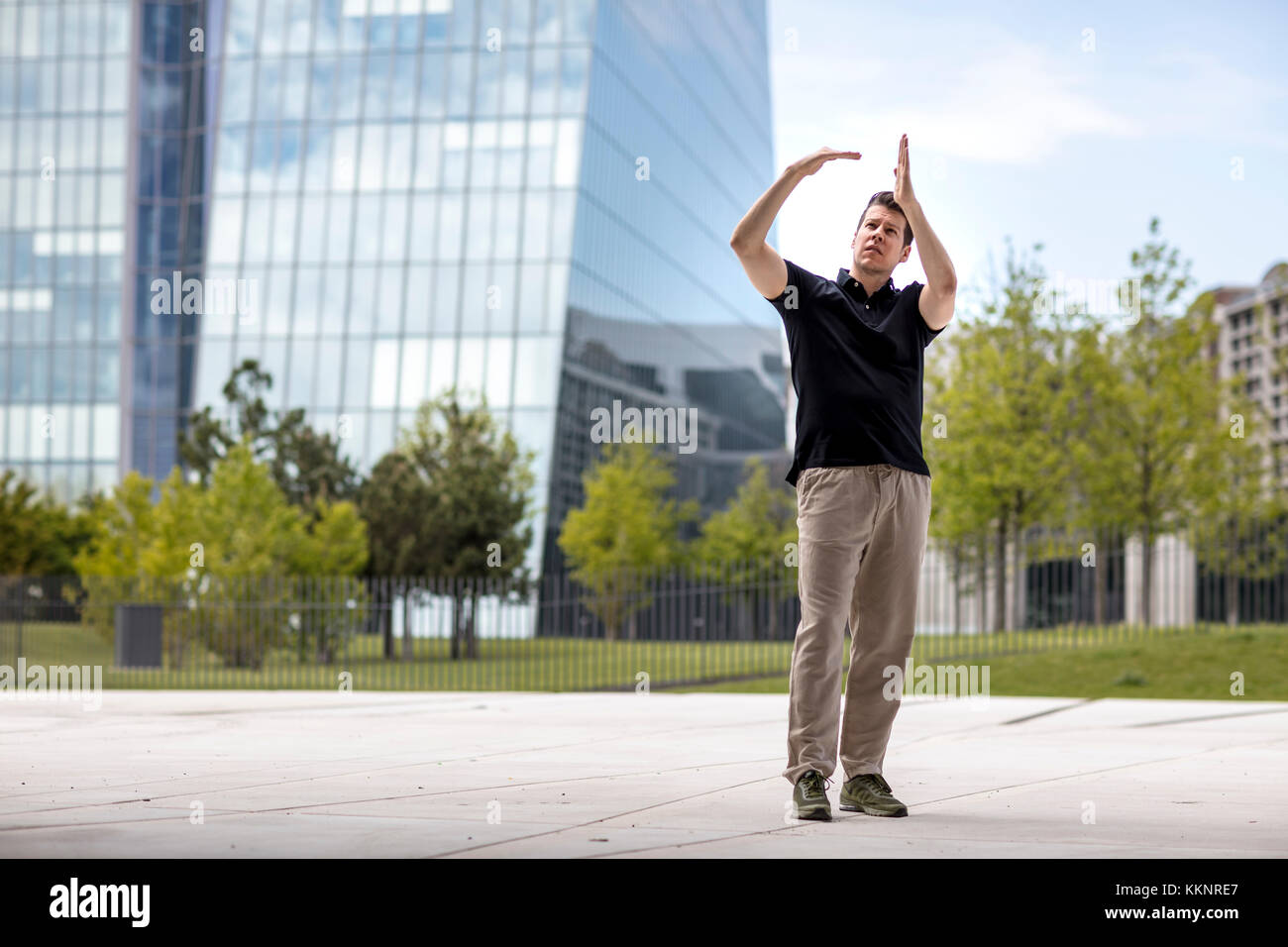 A man making hand gestures while standing in front of modern glass ...