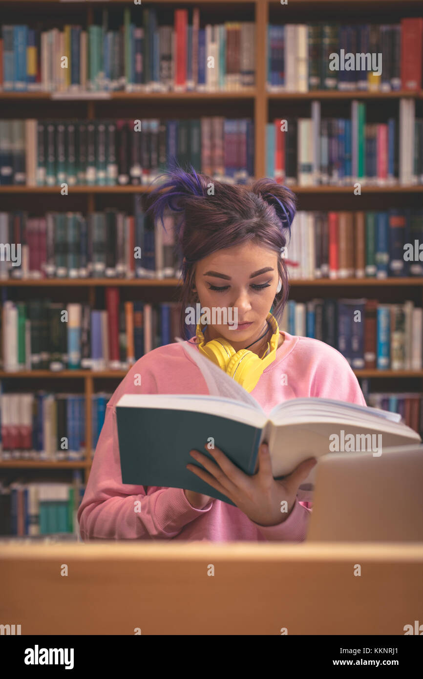 Girl reading book in library Stock Photo - Alamy